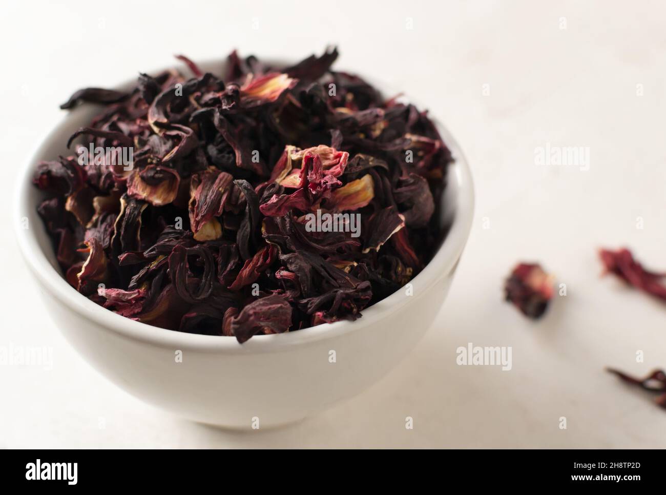 Dry leaves of hibiscus lie in a white bowl on a white background. Dried ...