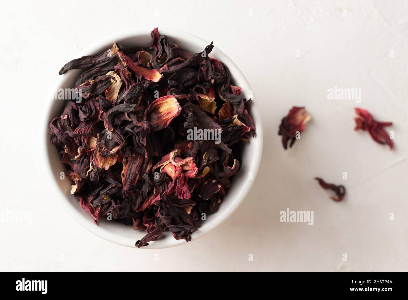 Dry leaves of hibiscus lie in a white bowl on a white background. Dried ...