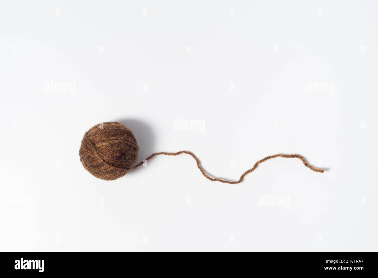 Dark brownish ball of yarn with loose thread on white background Stock ...