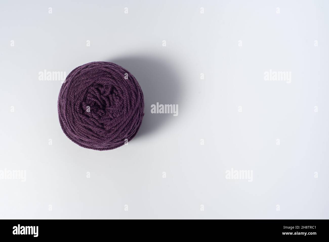 Large dark purple ball of yarn on white background Stock Photo - Alamy
