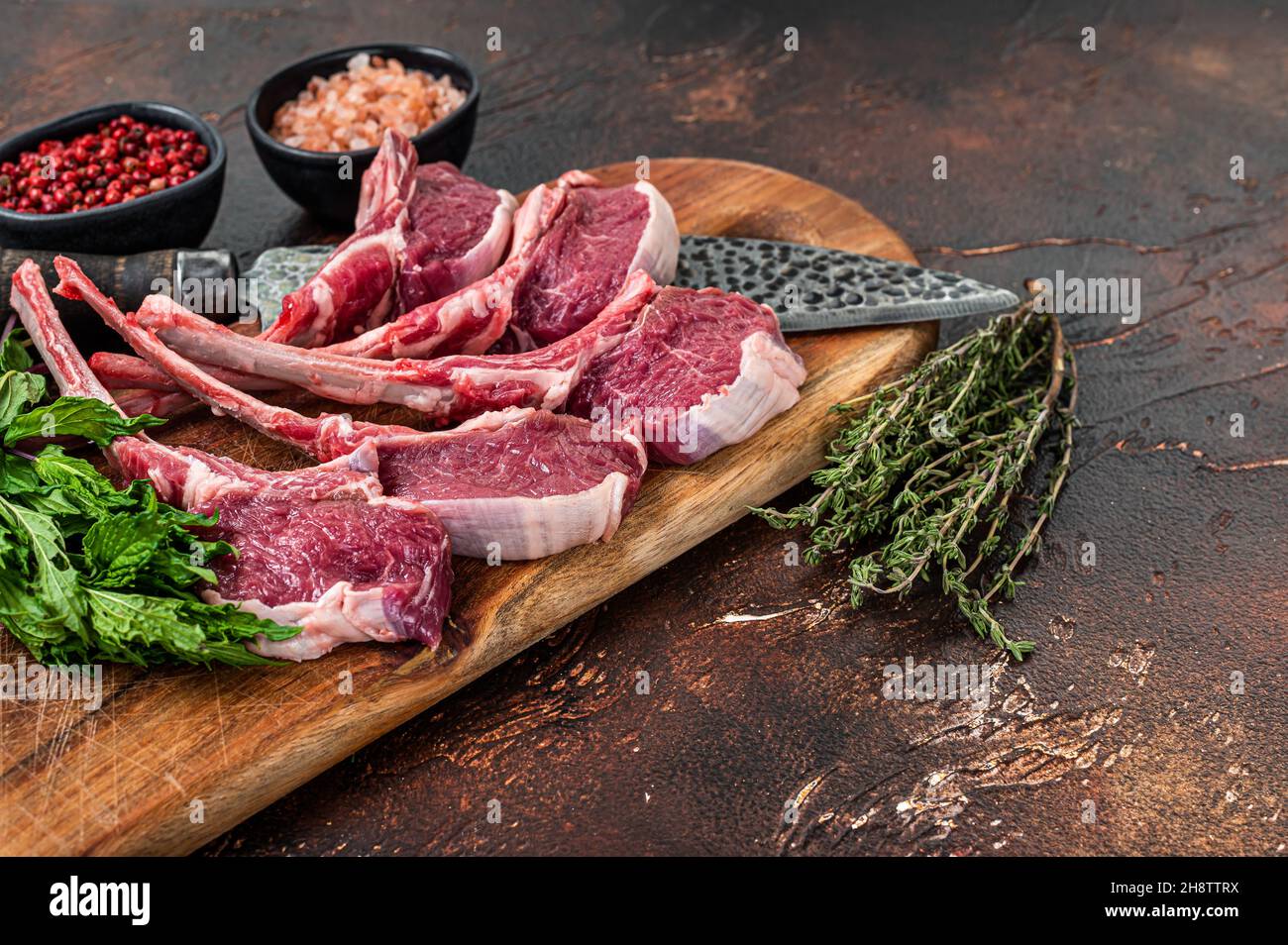 Raw lamb, mutton chops steaks on a wooden board. Dark background. Top ...