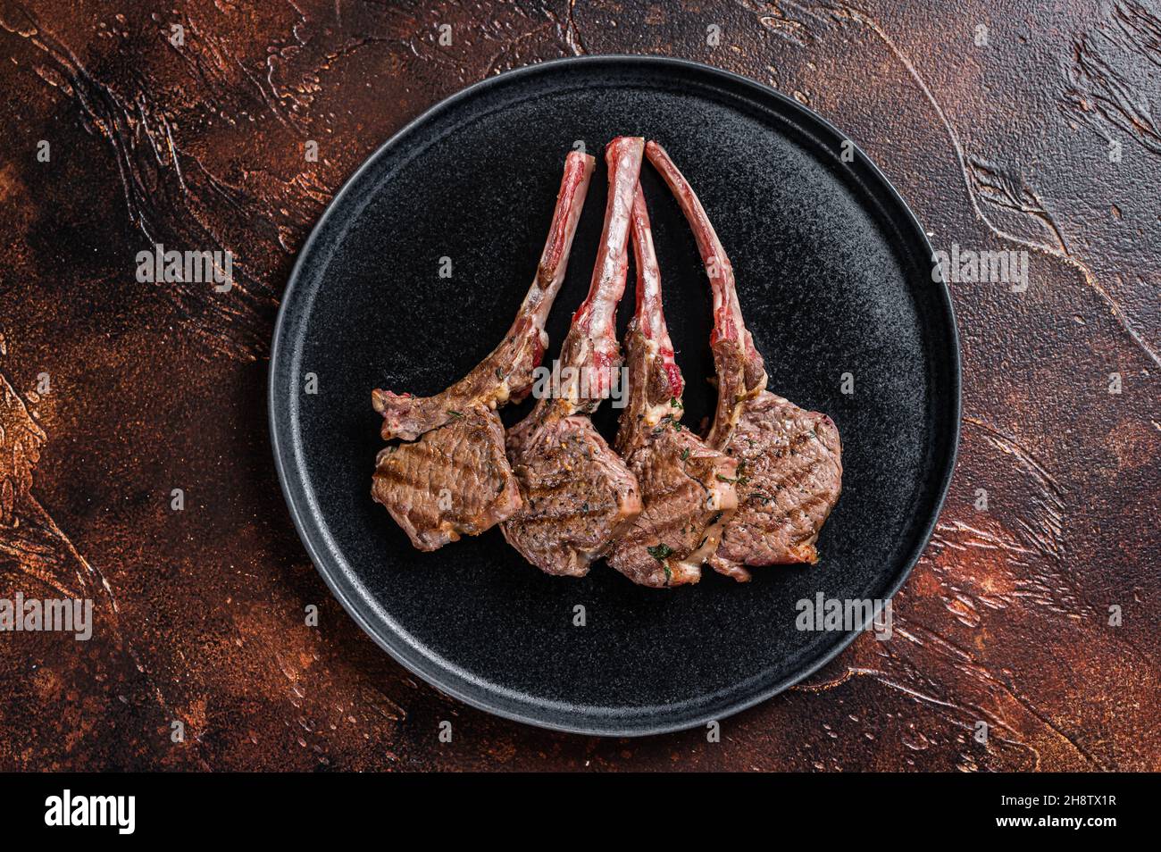 BBQ Grilled lamb chops steaks in a plate. Dark background. Top view ...