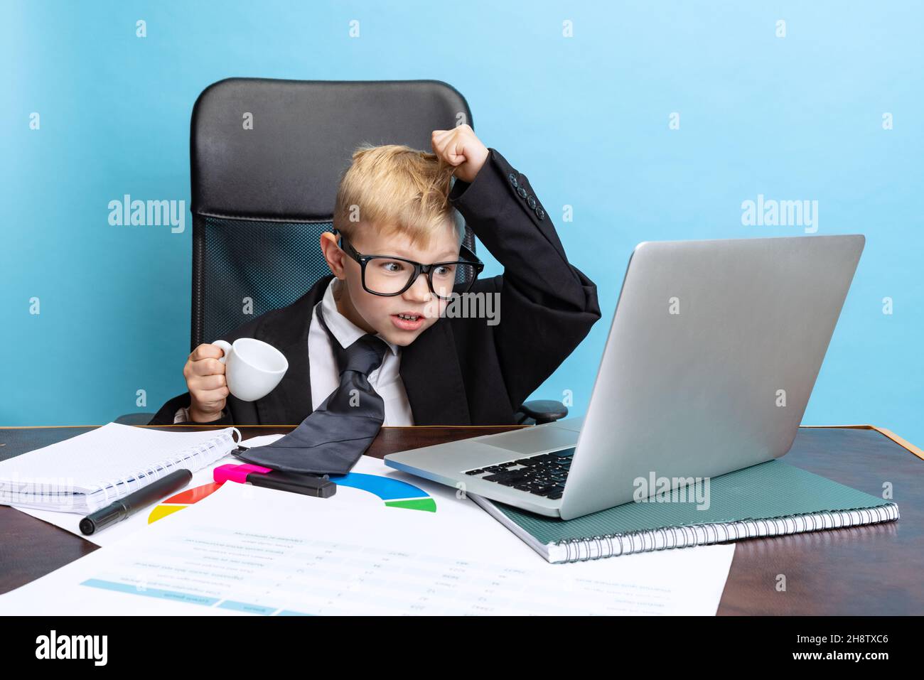 Portrait of little boy, child businessman in huge jacket suit sitting ...