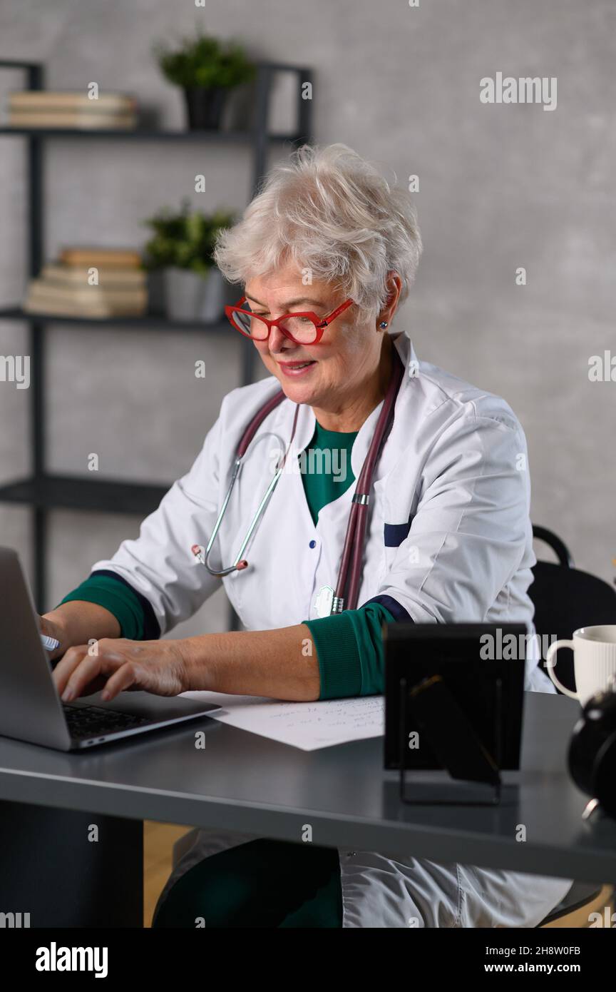 elderly woman doctor works at the computer. Telemedicine doctor talking ...