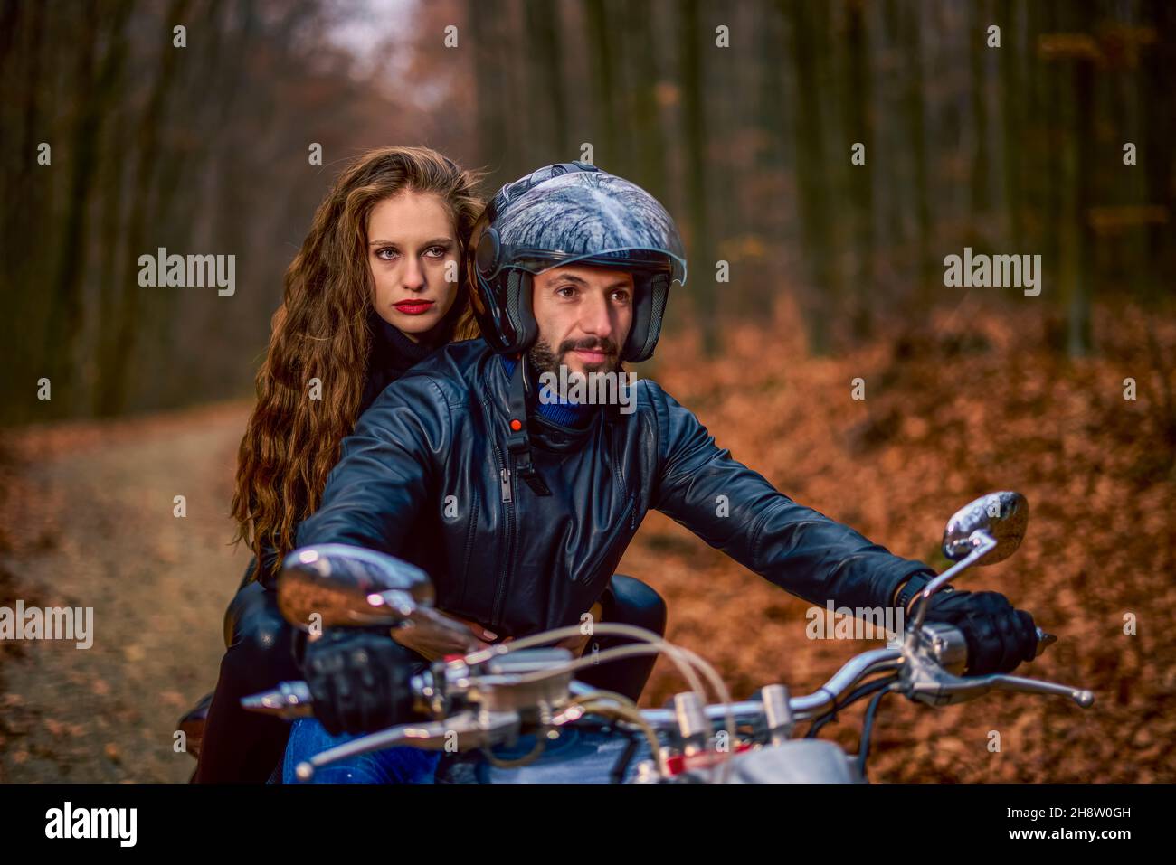 Couple of motorcyclists with a chopper in the woods in the fall Stock ...