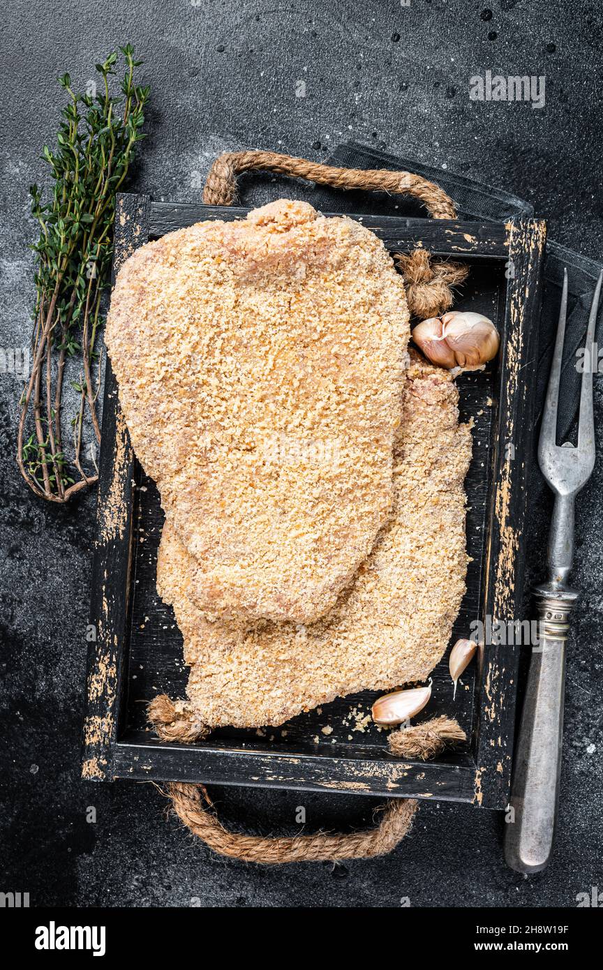 Homemade German Wiener Raw schnitzel in a wooden tray. Black background ...