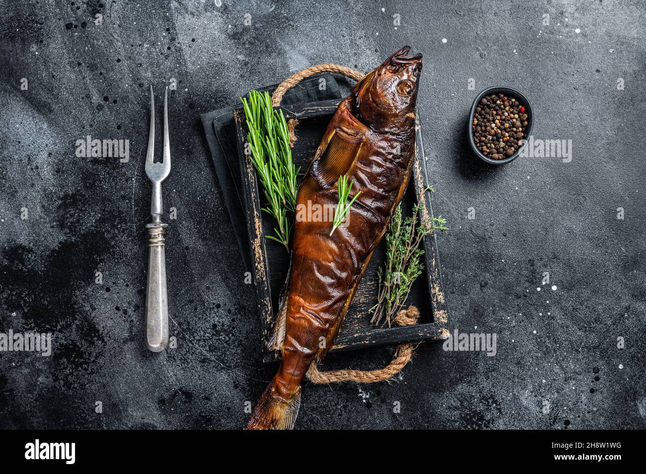 Hot smoked pike perch or zander fish in a wooden tray. Black background ...