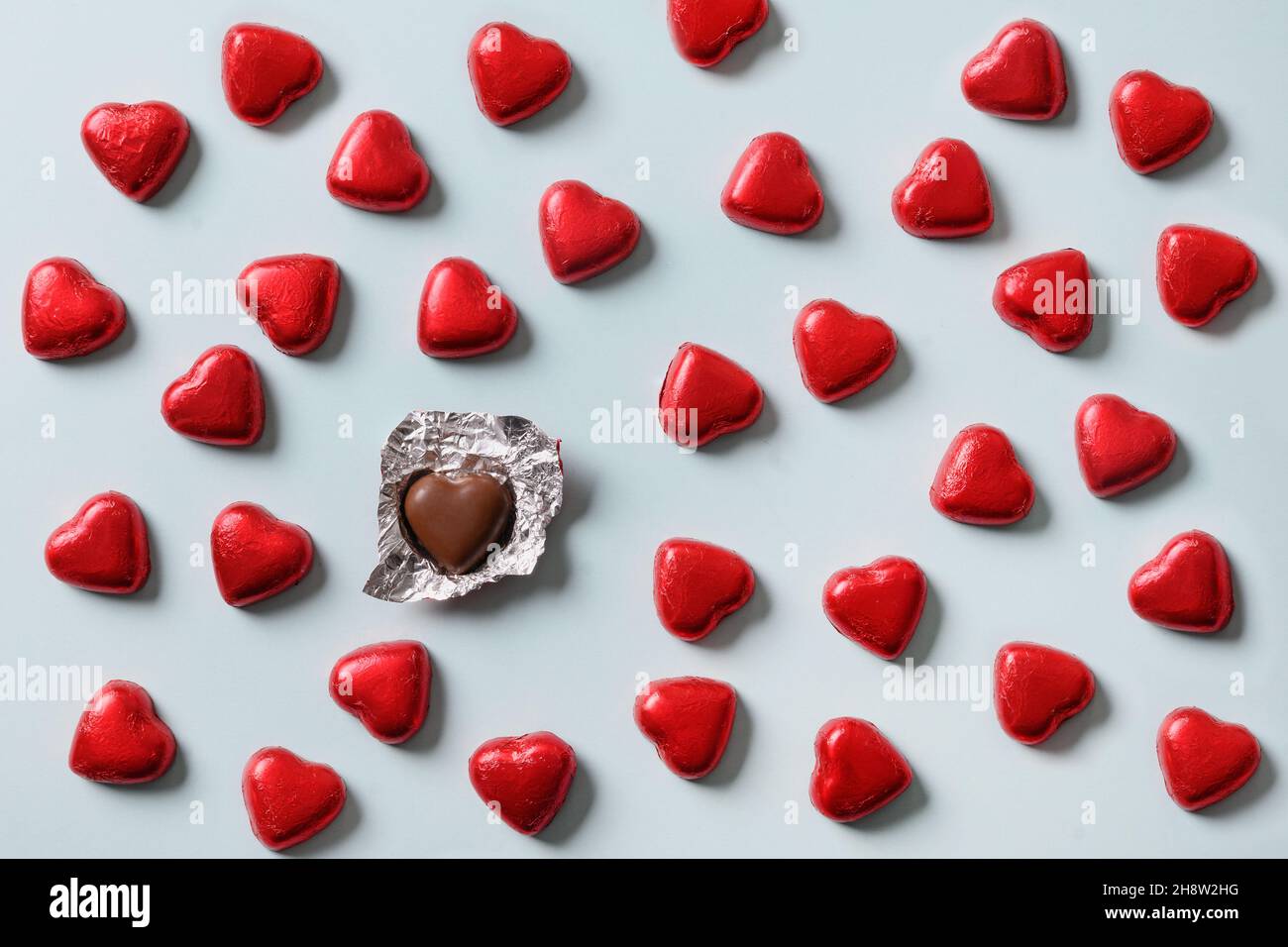 Romantic red chocolate sweets as heart in red foil and one open sweet ...