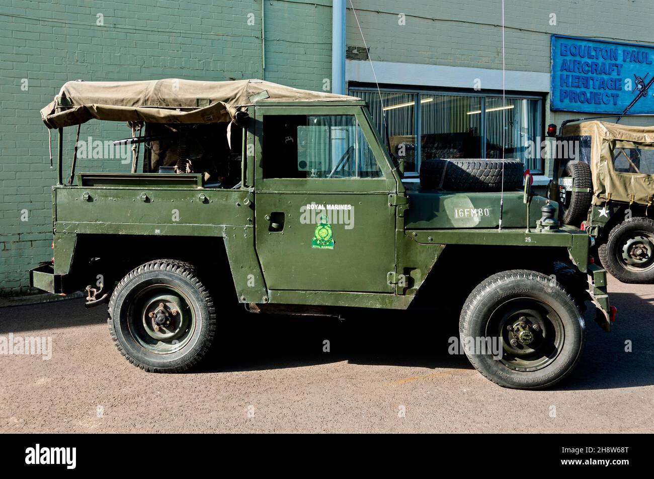 An ex-military Land Rover with a machine gun in the back parked outside ...