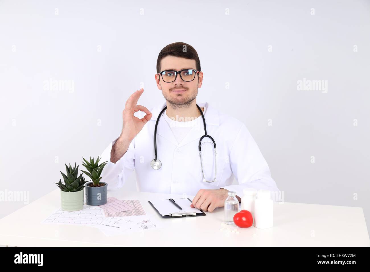 Doctor intern sitting at workplace on white background Stock Photo - Alamy