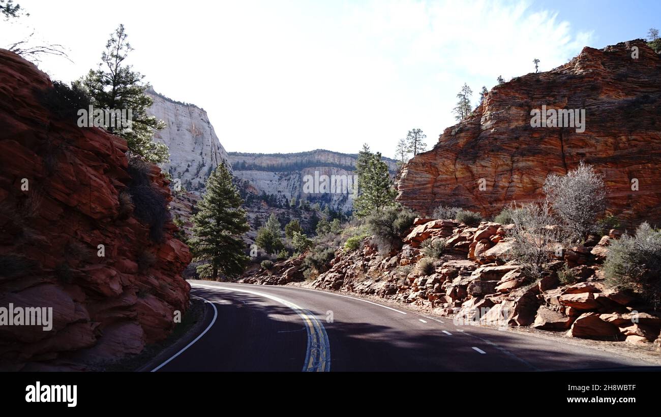 Asphalt highway through the steep red cliffs in the Zion National Park ...