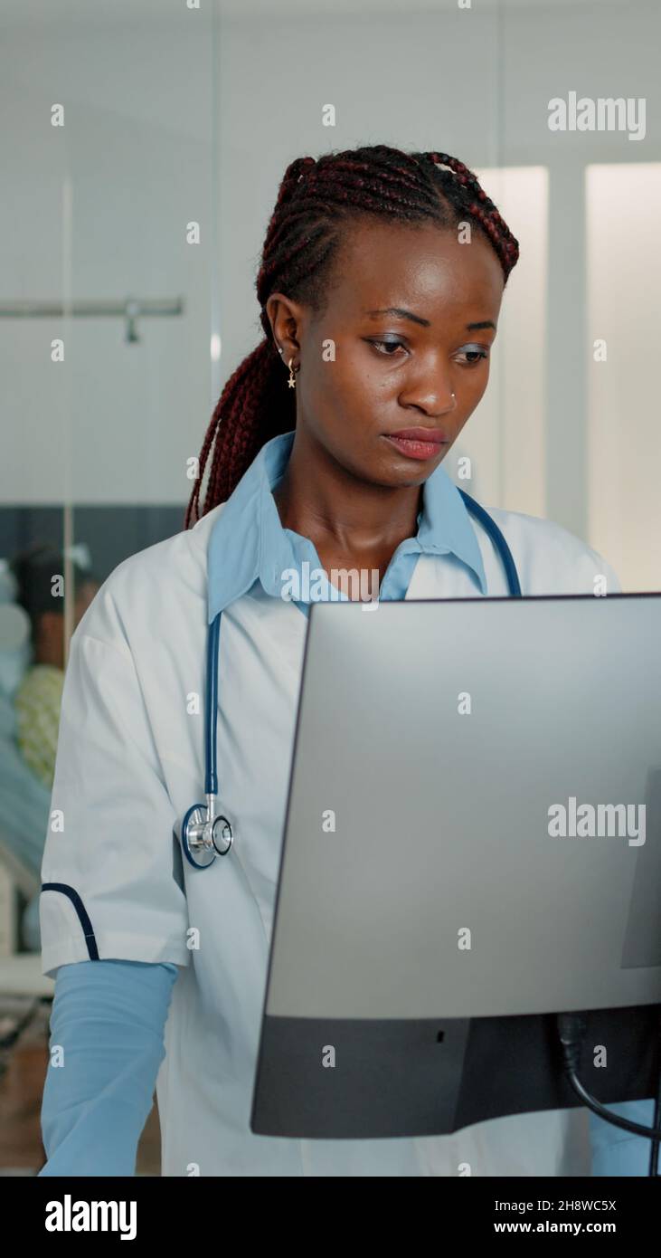 Woman working as doctor with stethoscope using computer to find patient ...
