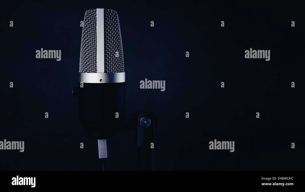 Single microphone on dark blue wall background Stock Photo - Alamy