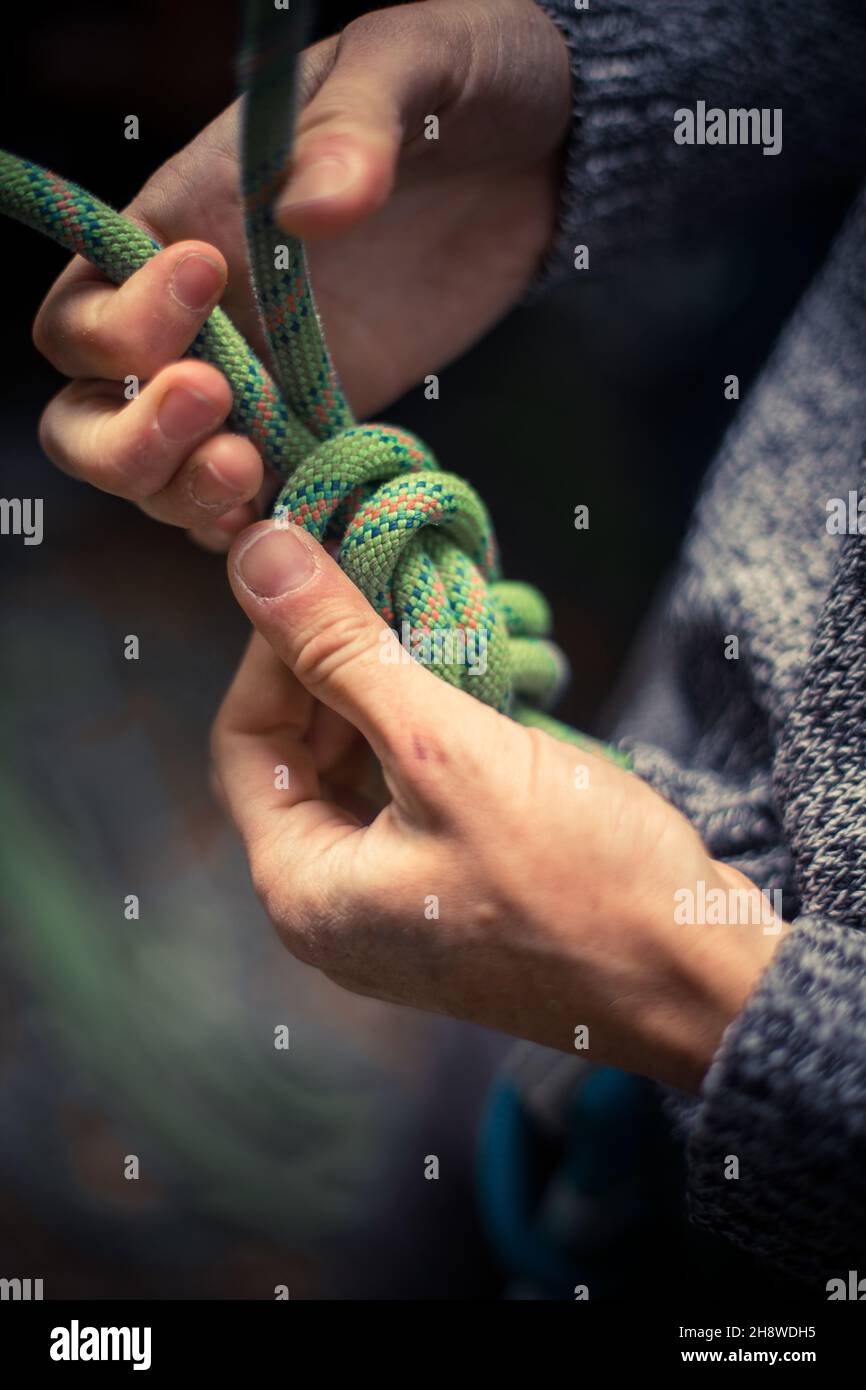 Detail with a climber's hands tying a figure eight know to the harness ...