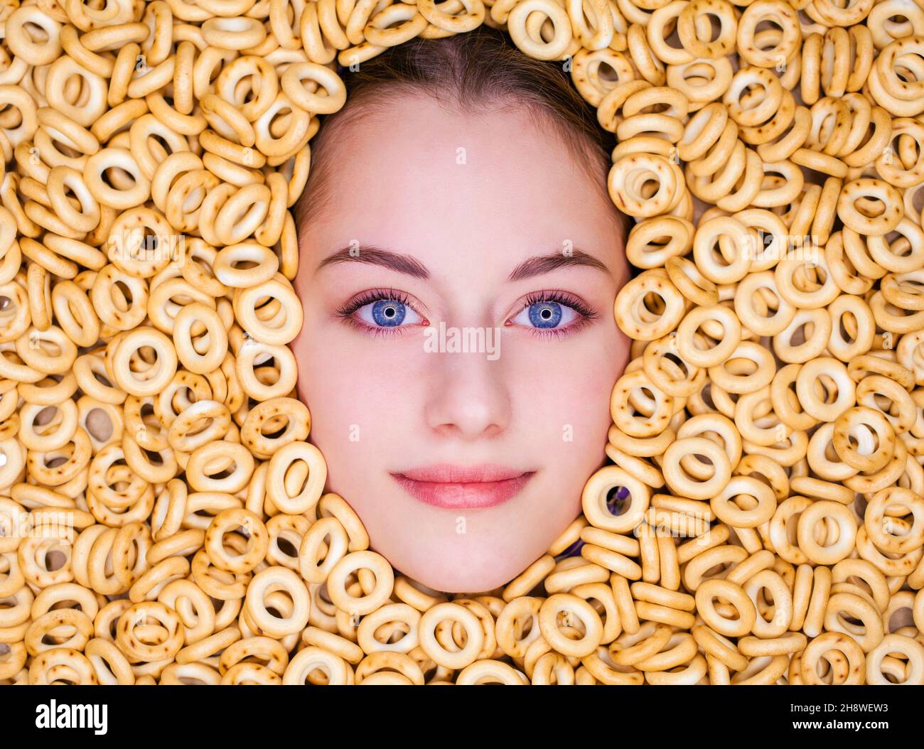 Young beautiful woman face in little fresh bagels Stock Photo - Alamy