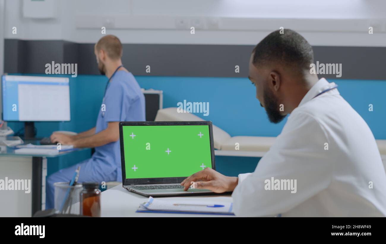 African american physician doctor looking at mock up green screen ...