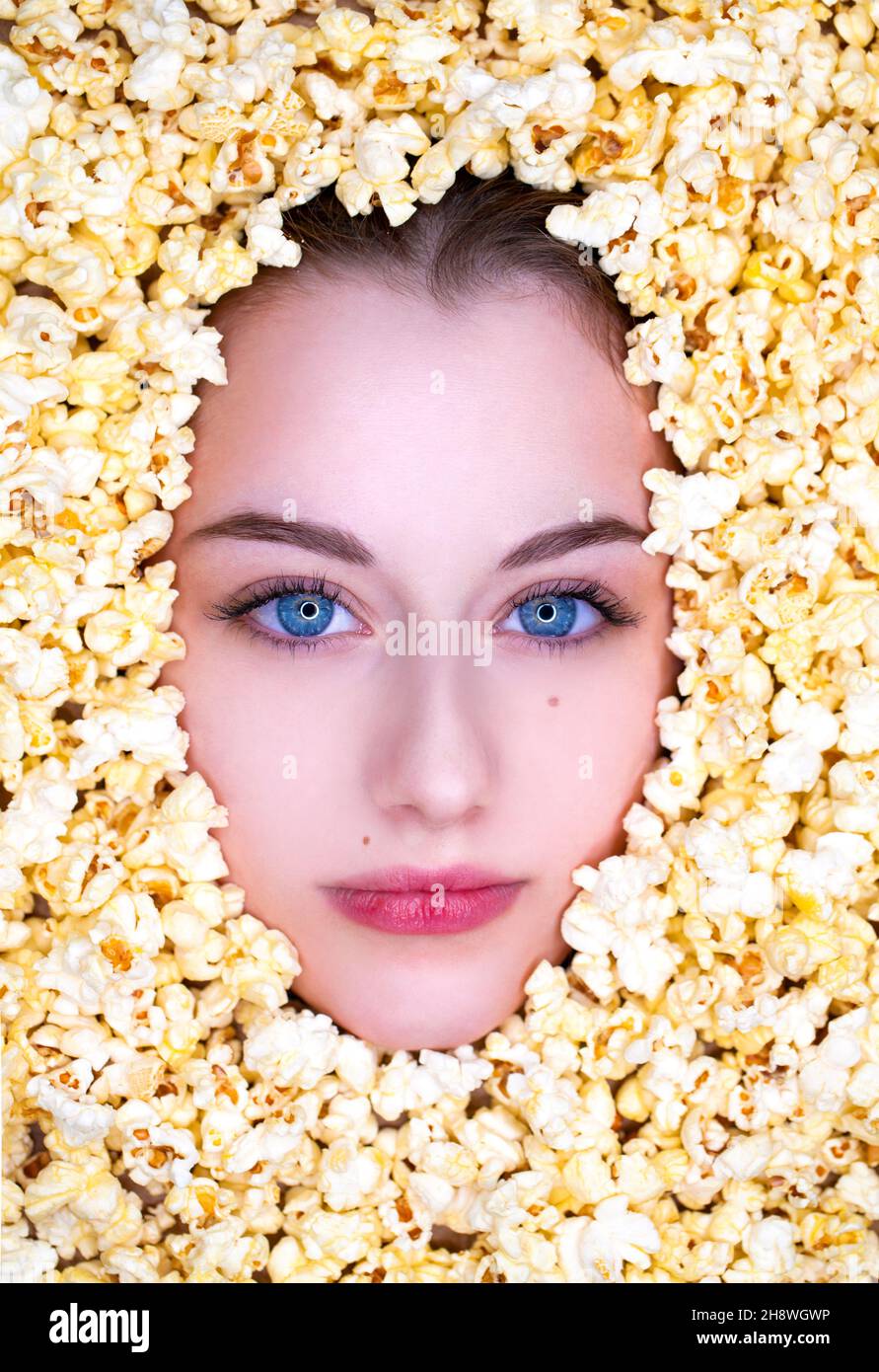 The face in popcorn. Portrait of a young beautiful girl on a background ...