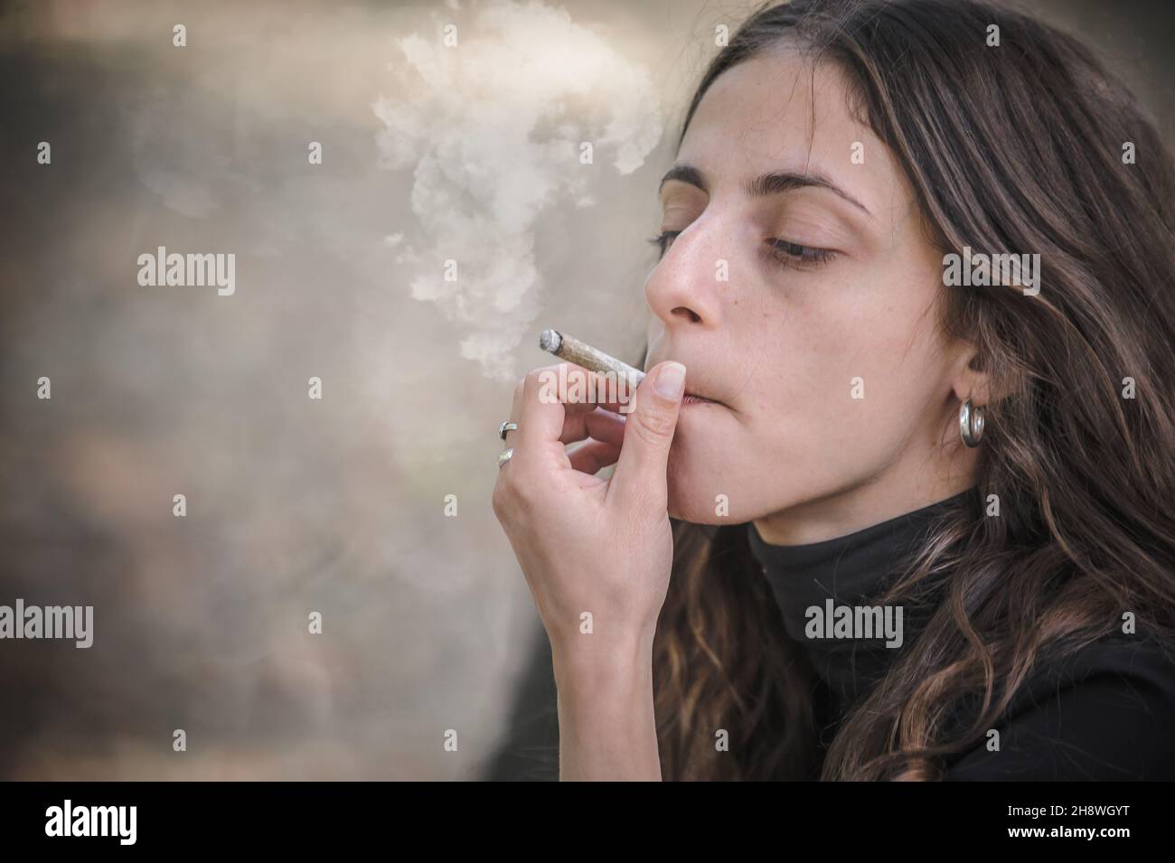 Closeup detail view of young woman smoke cannabis marijuana ganja or ...