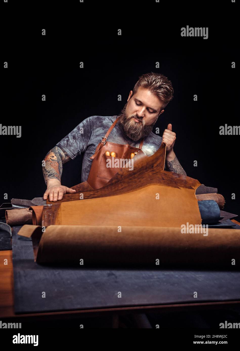 Skinner working with leather using crafting tools in the place of work ...