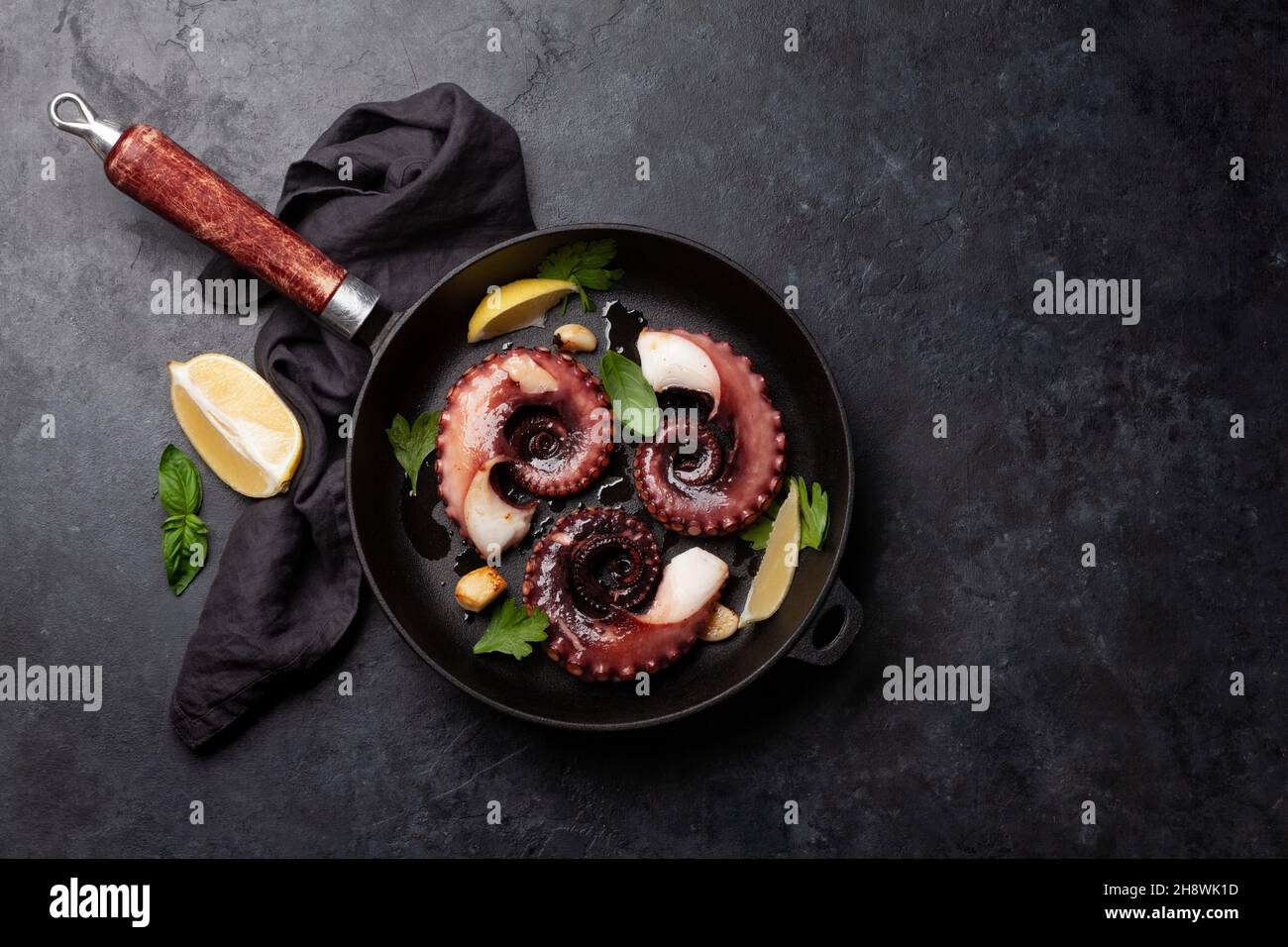Grilled octopus with herbs and spices on frying pan. Top view flat lay ...