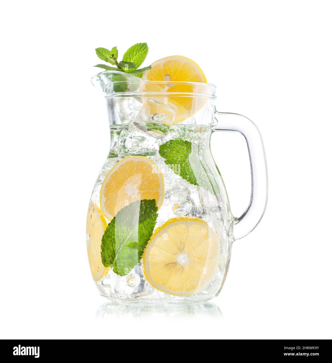 Lemonade pitcher with lemon, mint and ice cubes. Over yellow background ...
