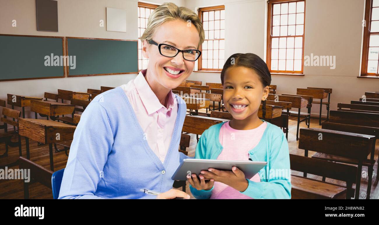 Portrait of smiling blond teacher helping schoolgirl with digital ...