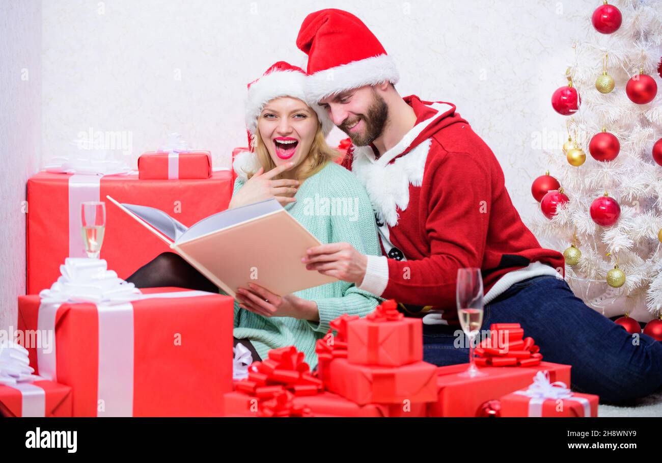 Family cuddle near christmas tree while looking family photo album ...