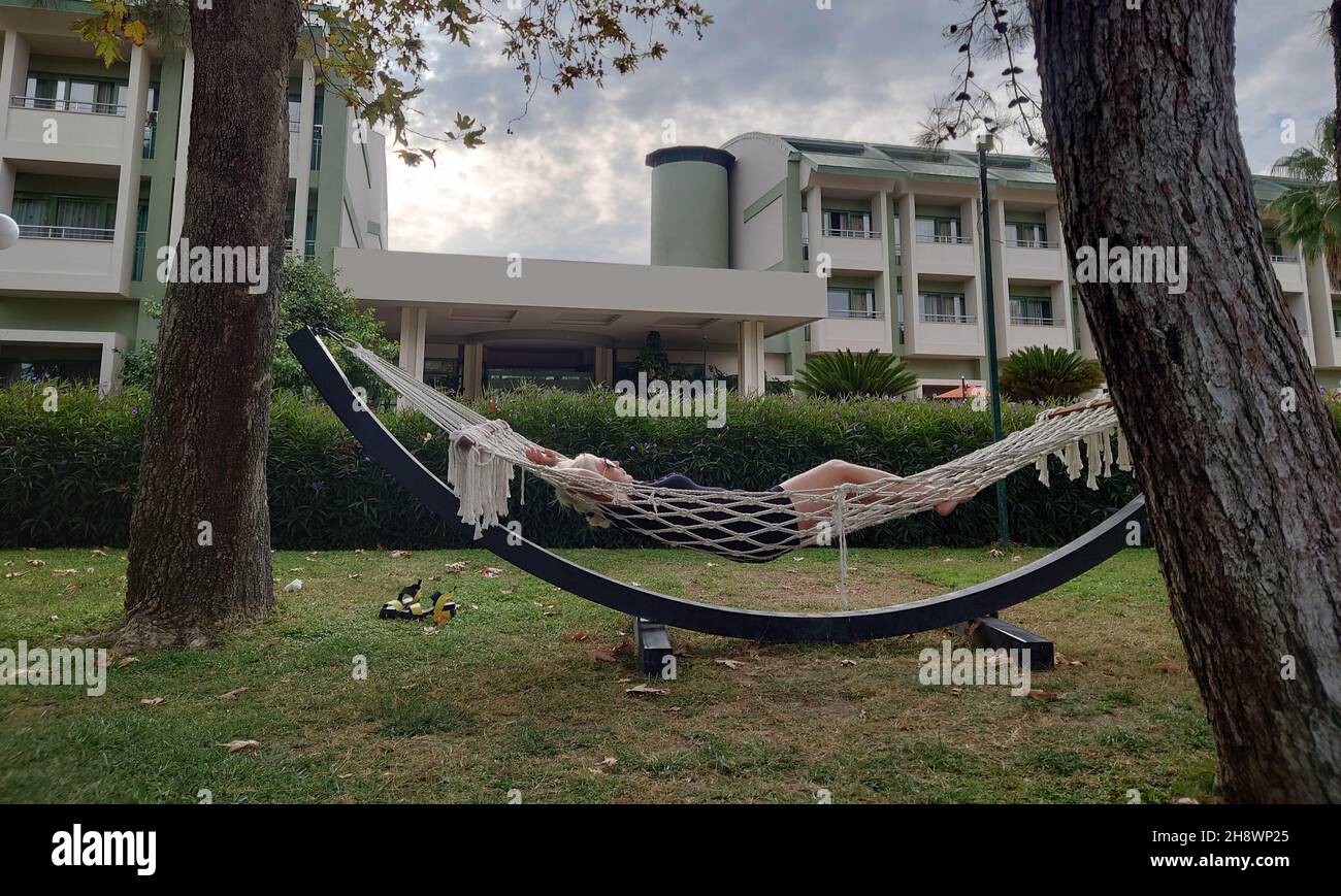Woman relaxing in a modern freestanding hammock in the garden of a ...