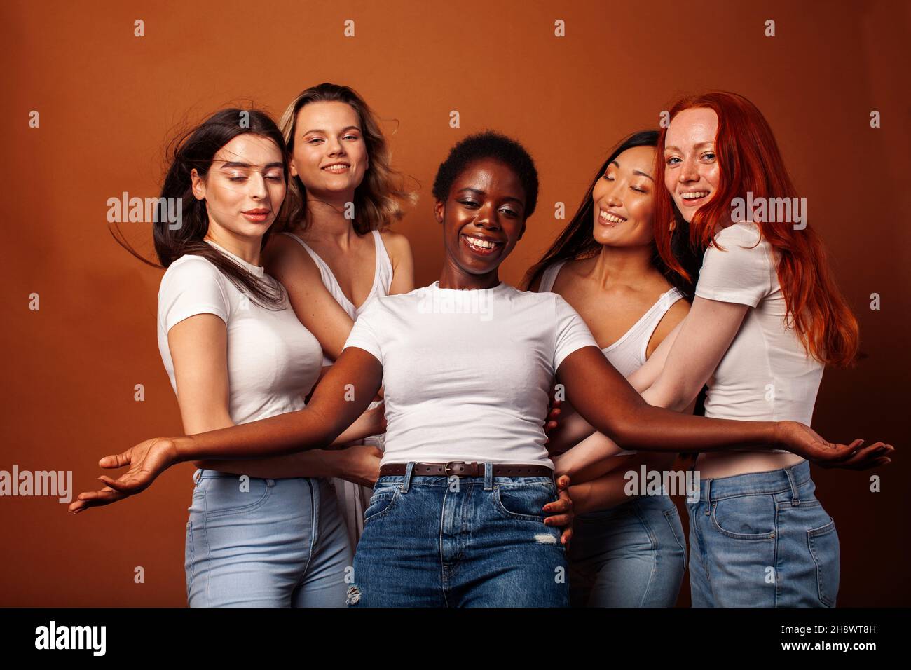 young pretty african and caucasian women posing cheerful together on brown background, lifestyle ...