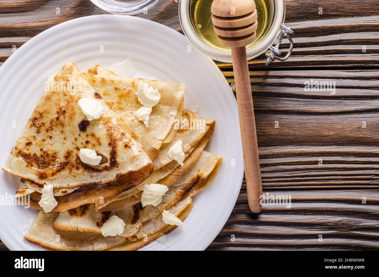 Flat lay of French crepes with butter and honey in ceramic dish on ...