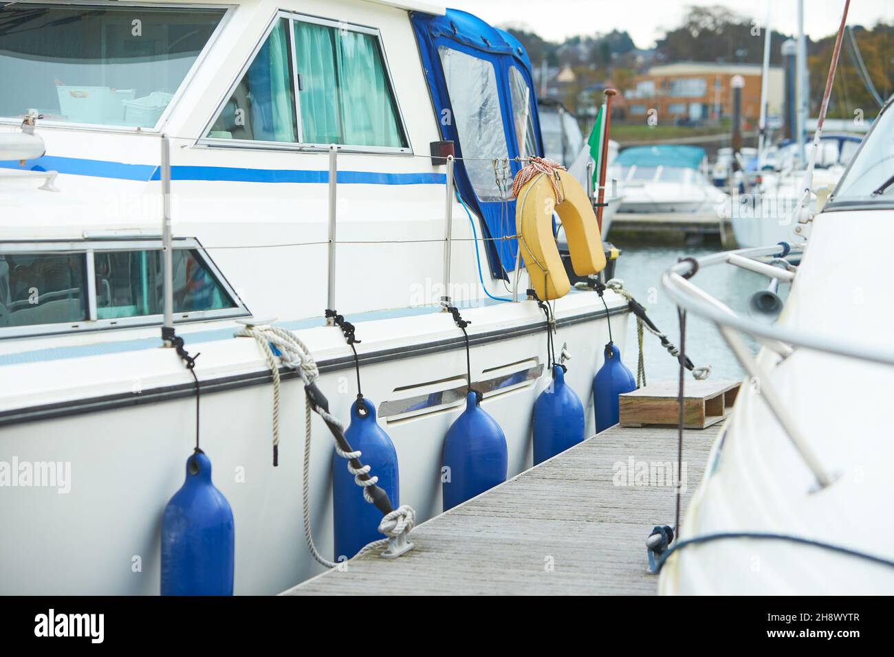 White boat white blue fenders suspended between a boat and dockside for ...