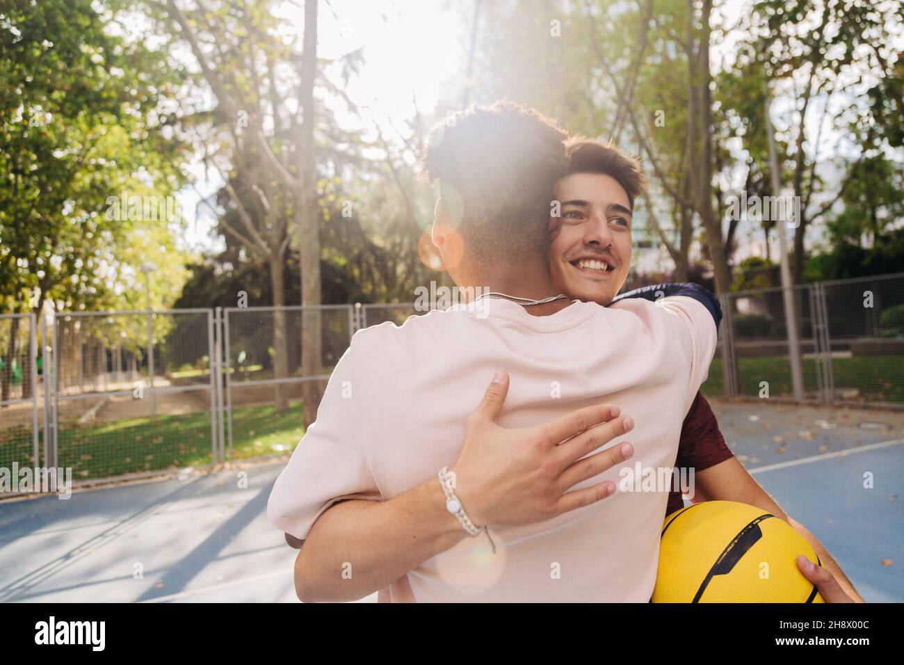 Positive multiracial friends players with basketball ball hugging each ...