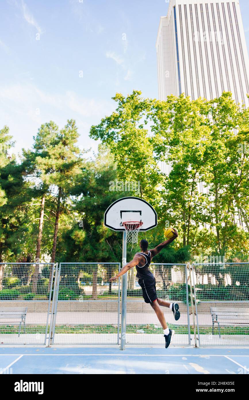 Back view of full body African American sportsman jumping and throwing ...