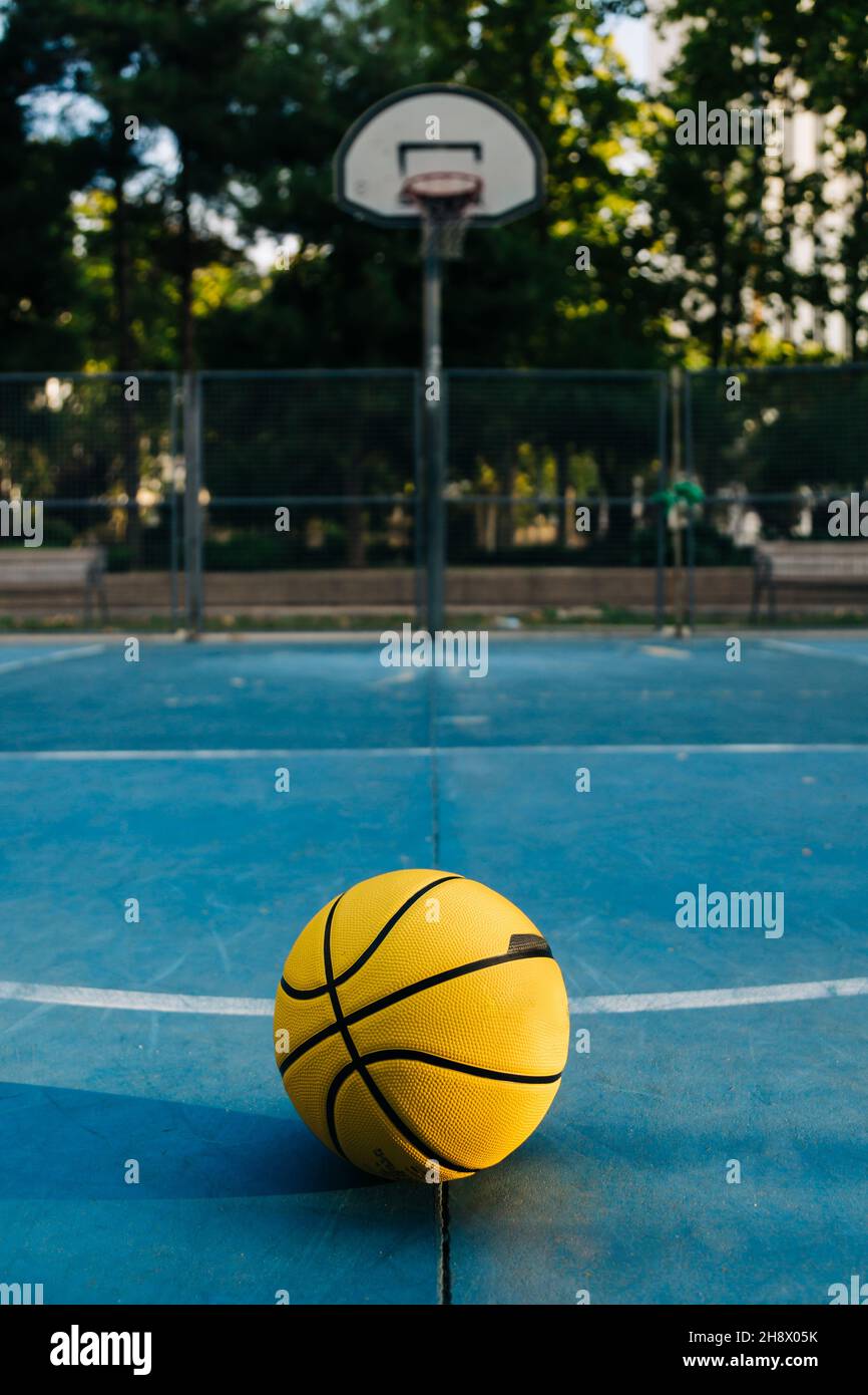 Yellow basketball ball with hoop and net placed on sports ground in ...