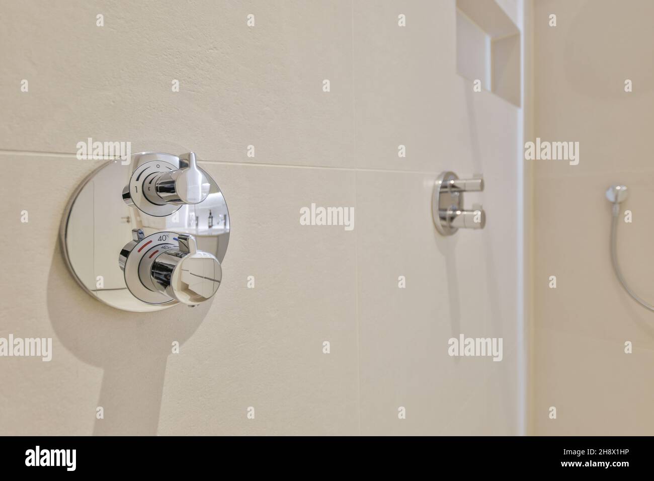 Round shower water switches on light tiled wall in shower in spacious ...