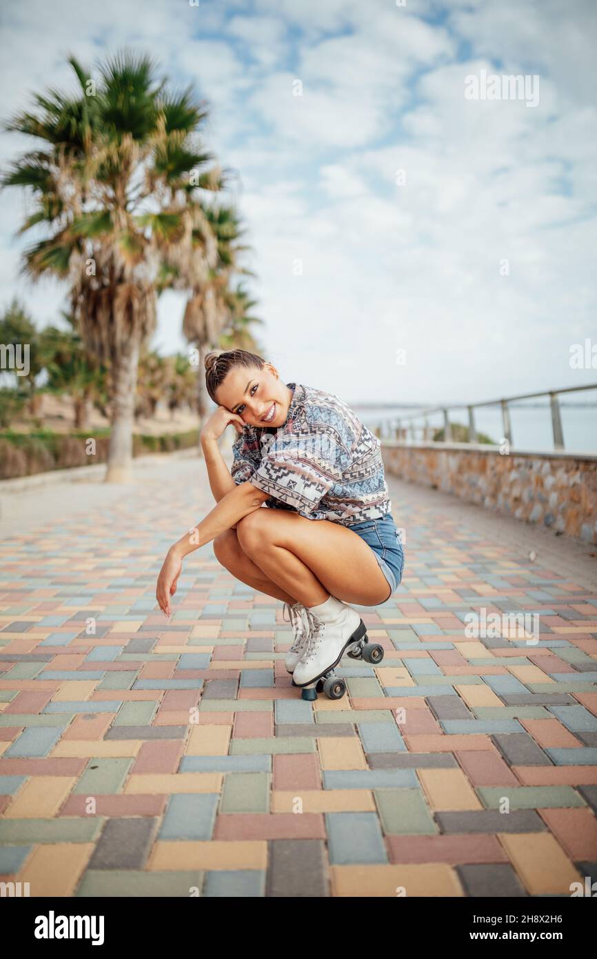 Full body side view of sportive female in roller skates on squatting on ...