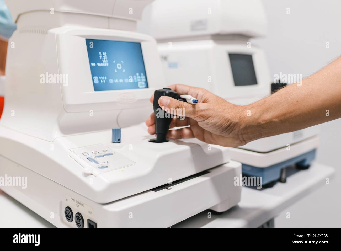 Crop anonymous male doctor ophthalmologist conducting autorefractometry ...