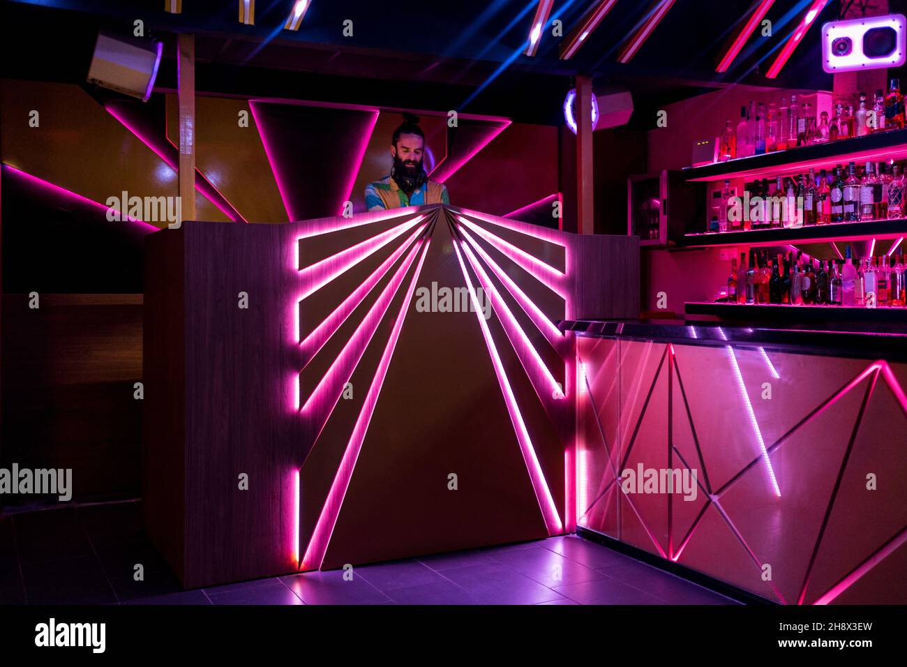 Concentrated young bearded male DJ standing at illuminated counter in ...