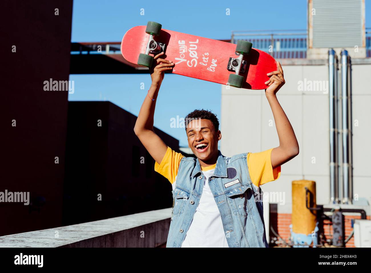 Handsome young black man holding a skateboard with outstretch arms ...
