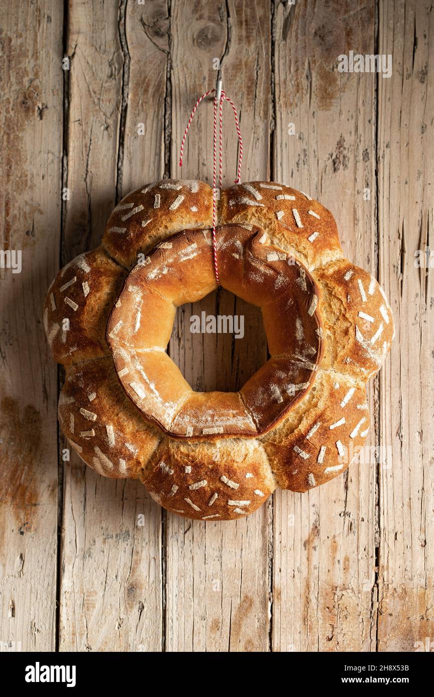 Baked round decorative bread with white patterns hanging on red thread ...