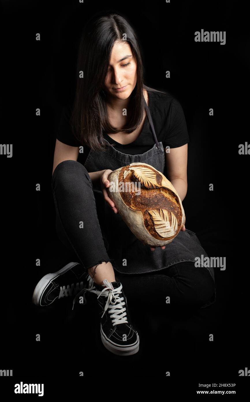 Full body of content female baker in apron with tasty loaf of bread ...