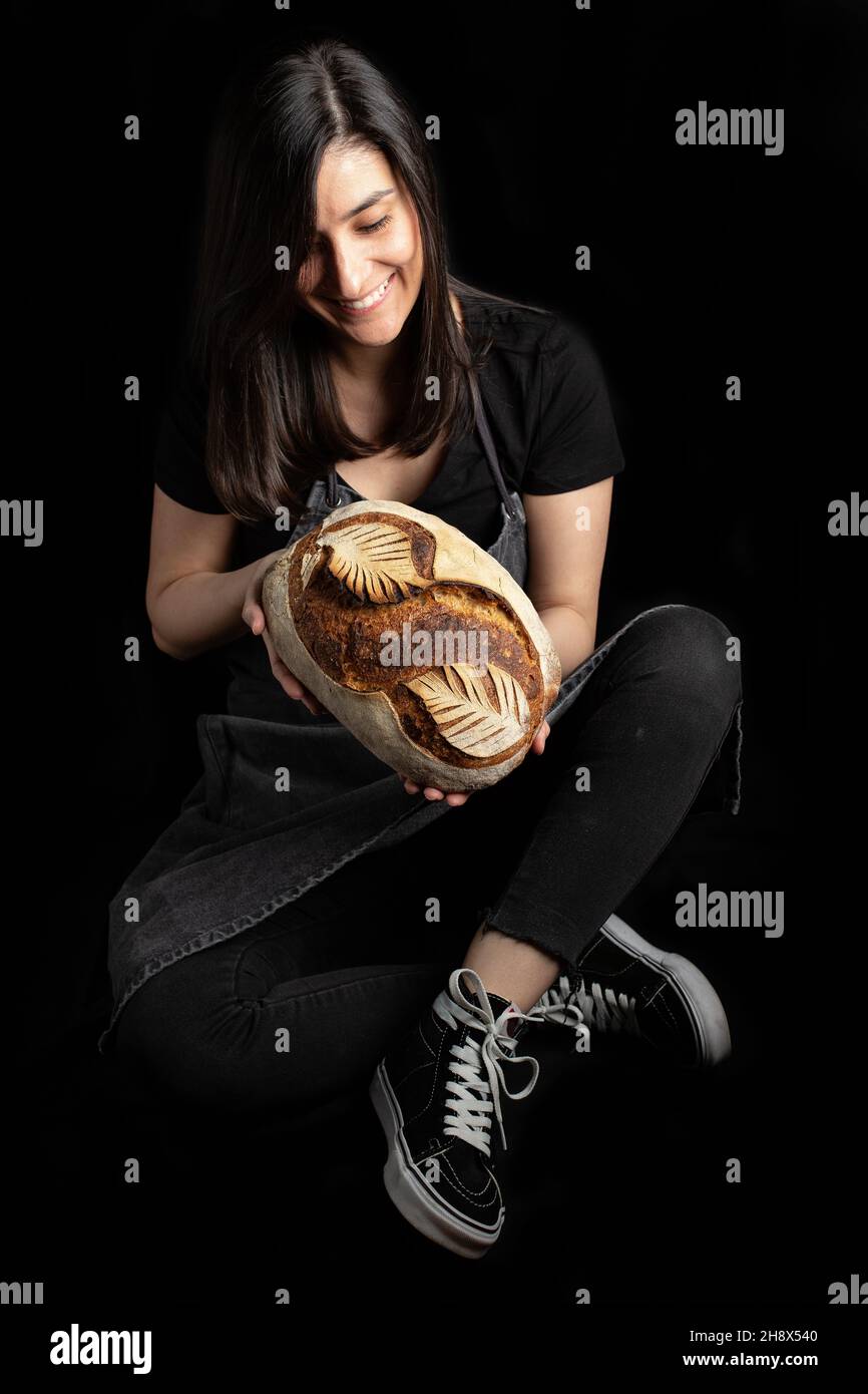 Full body of content female baker in apron with tasty loaf of bread ...