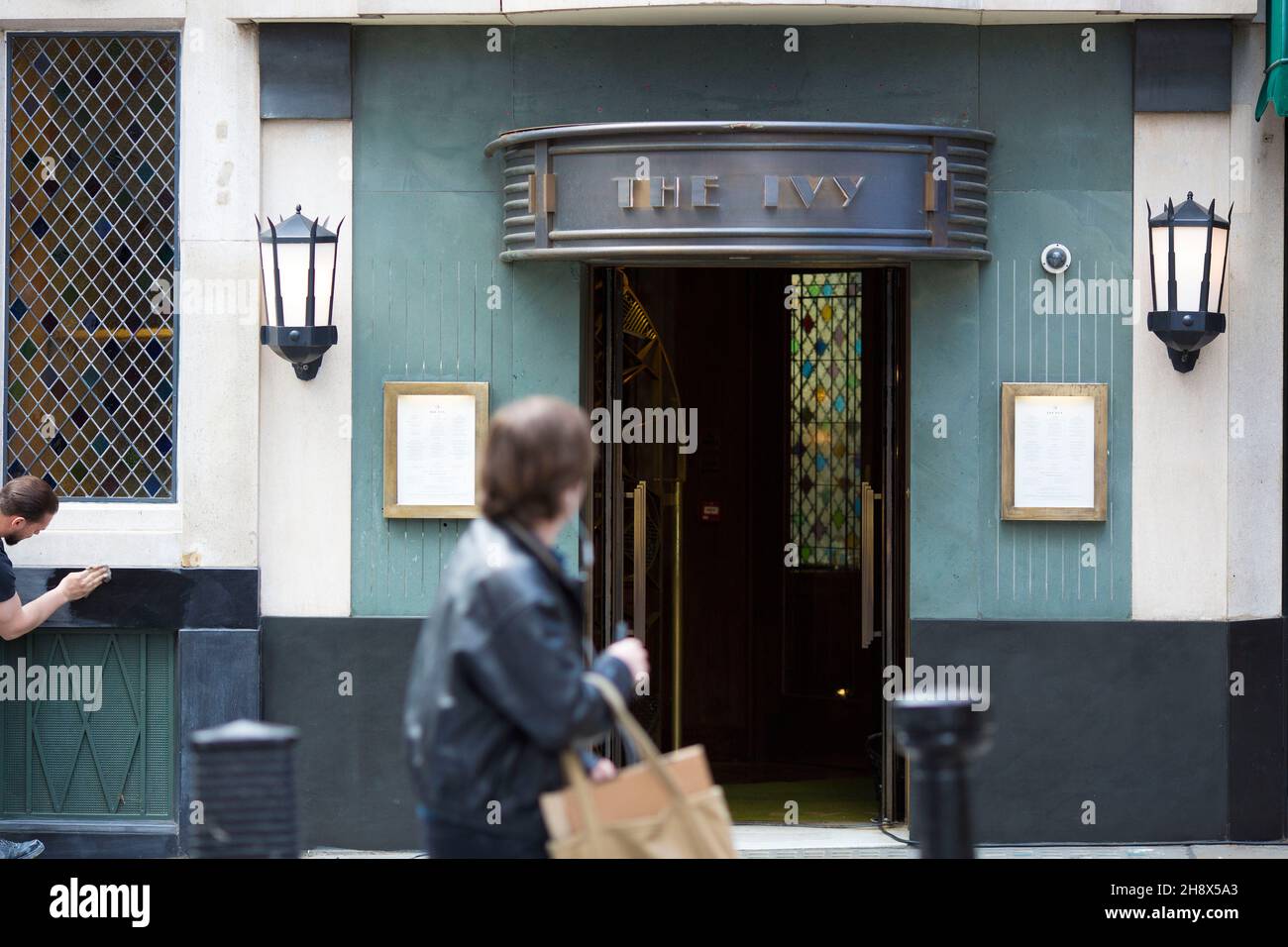 Workers brush up the traditional exterior at The Ivy restaurant in ...