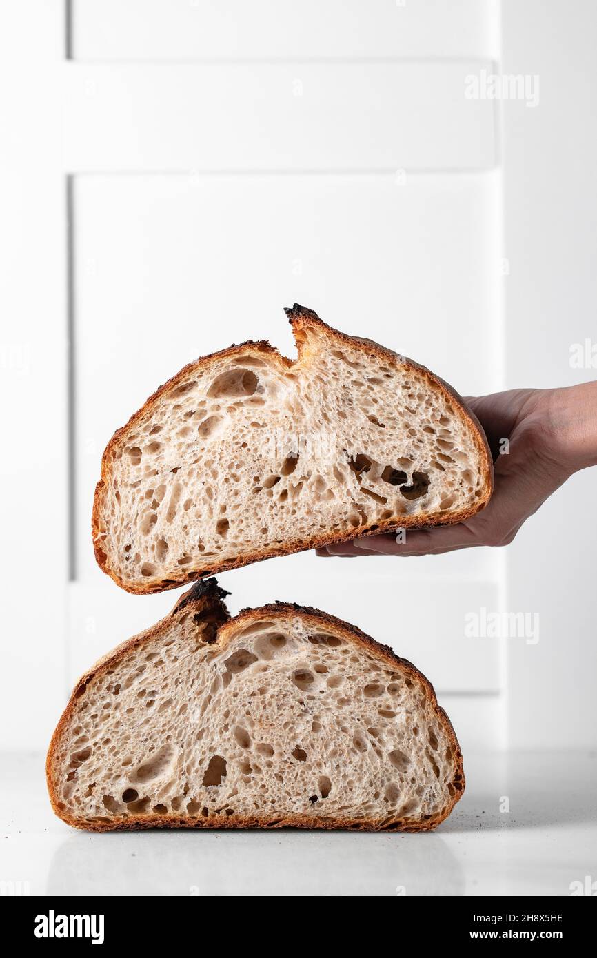 Crop anonymous person touching split sourdough bread with crunchy crust ...