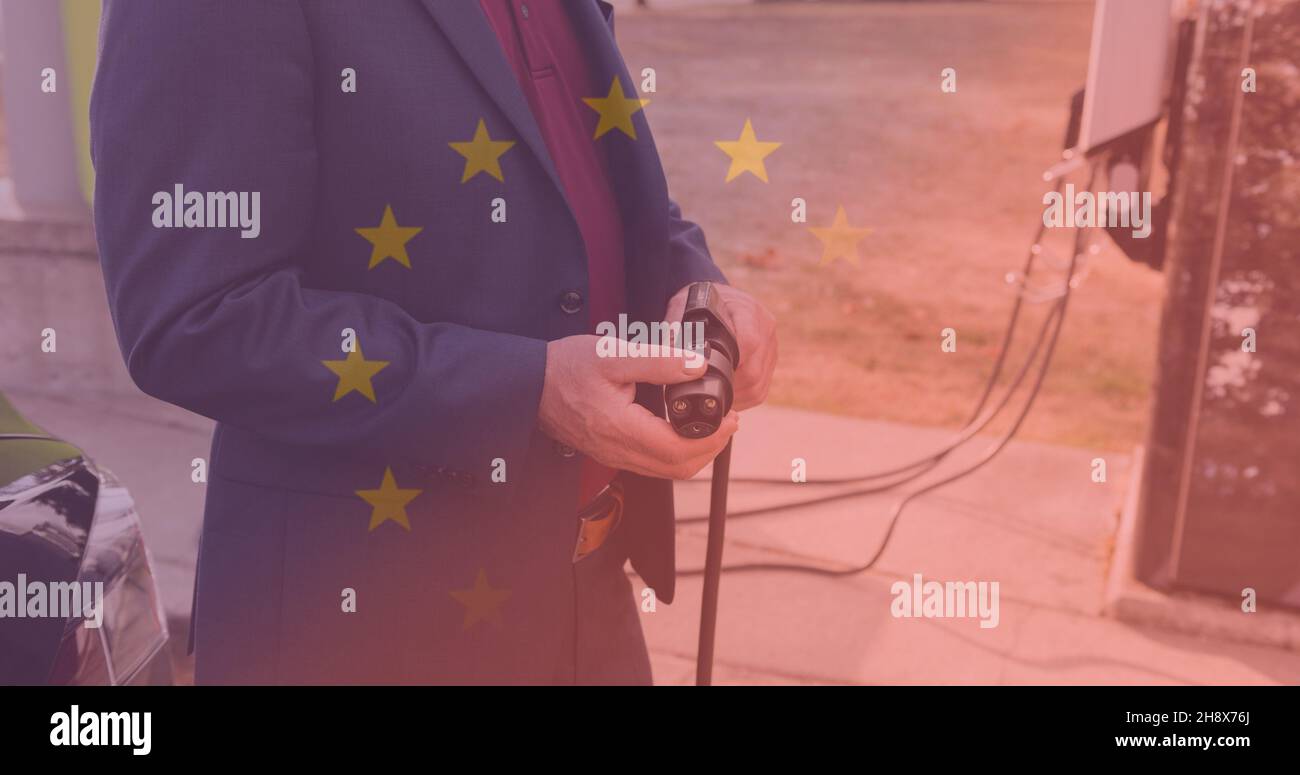 Double exposure of businessman holding electric vehicle charging plug ...
