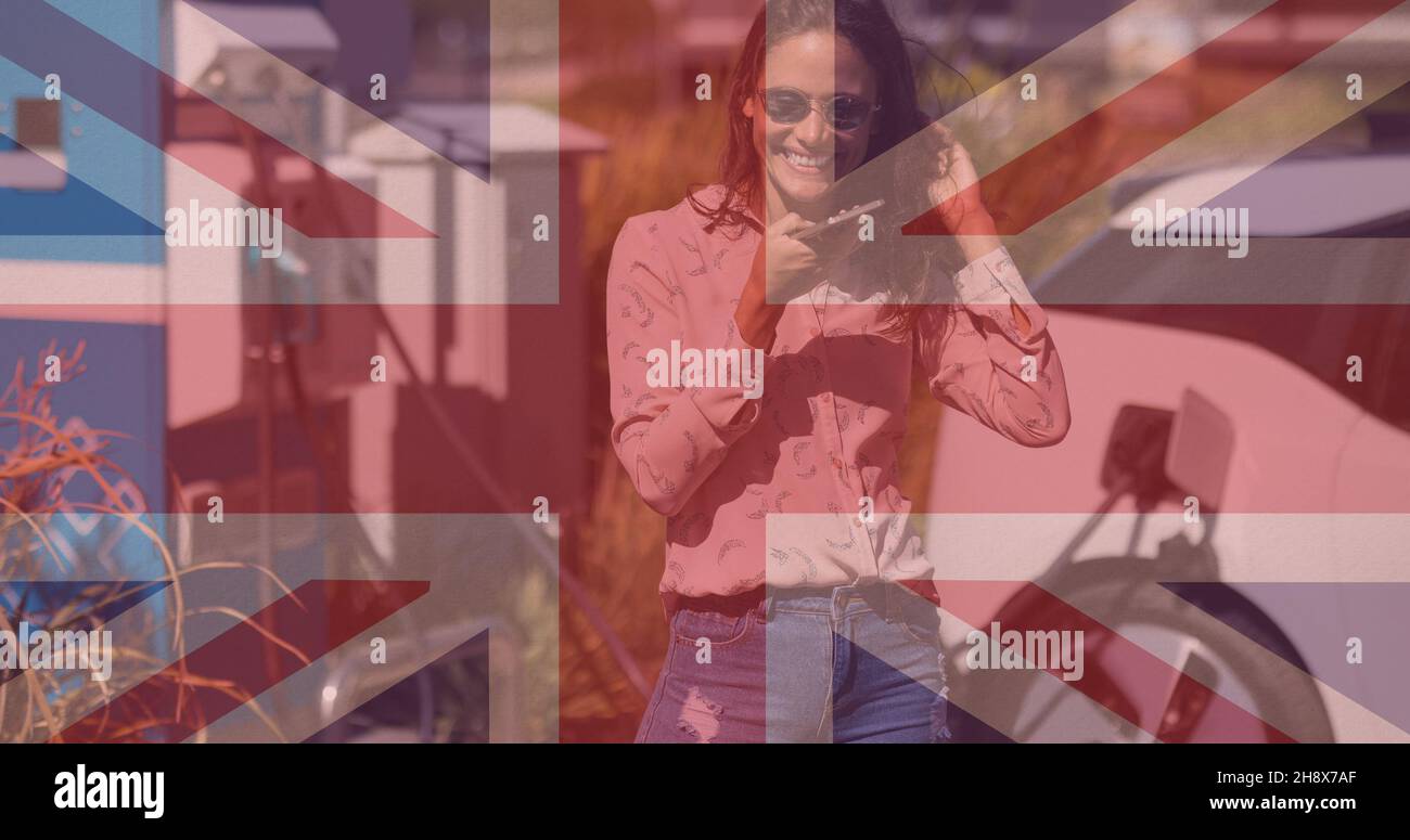 British flag over smiling young woman talking on mobile phone against ...