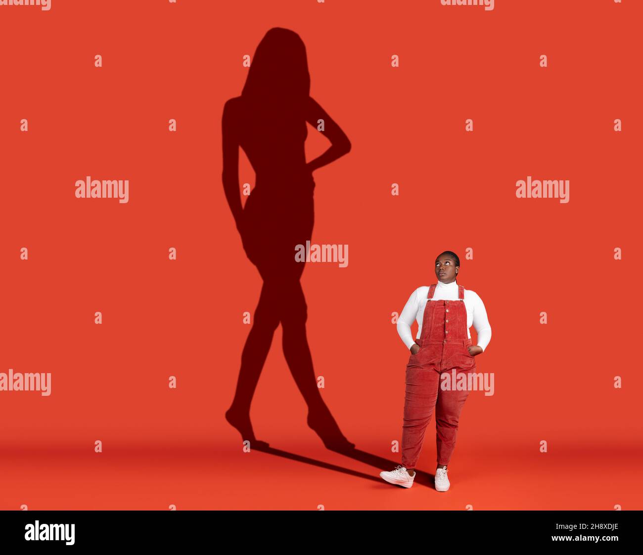Conceptual image with fat woman standing near wall with shadow of slim ...