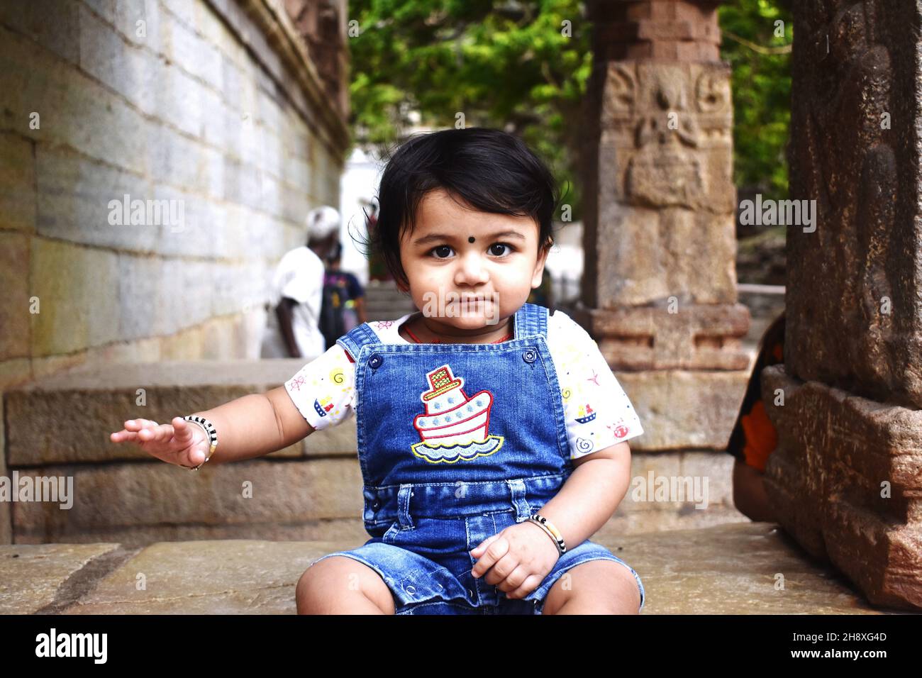 Cute Indian baby sitting on a stone in a park Stock Photo - Alamy