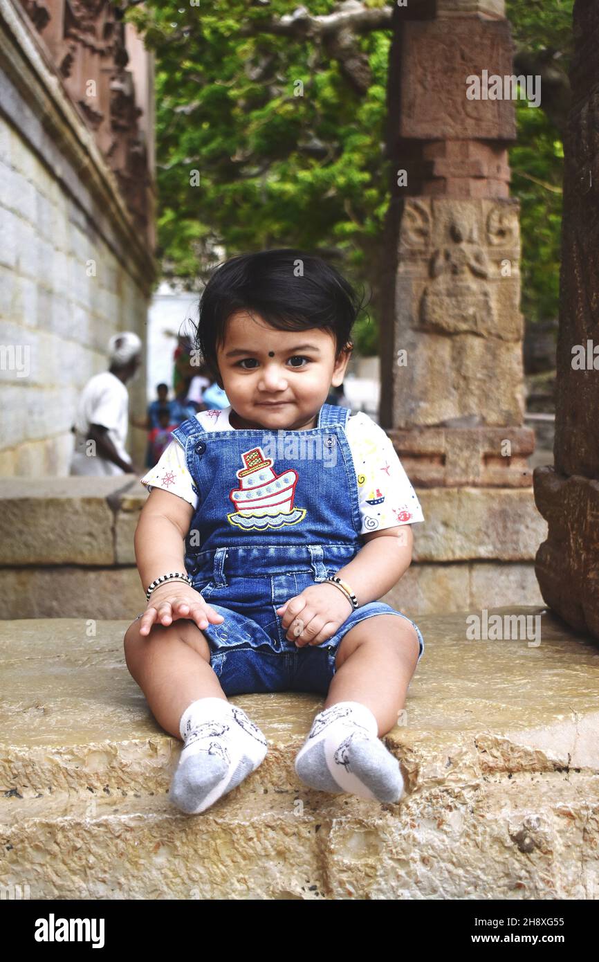 Cute Indian baby sitting on a stone in a park Stock Photo - Alamy