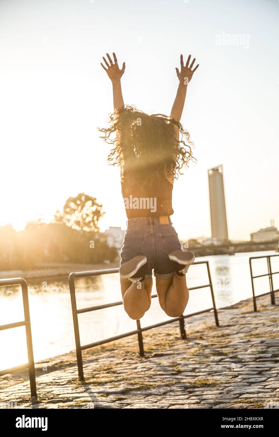 Woman from behind jumping celebrating success Stock Photo - Alamy